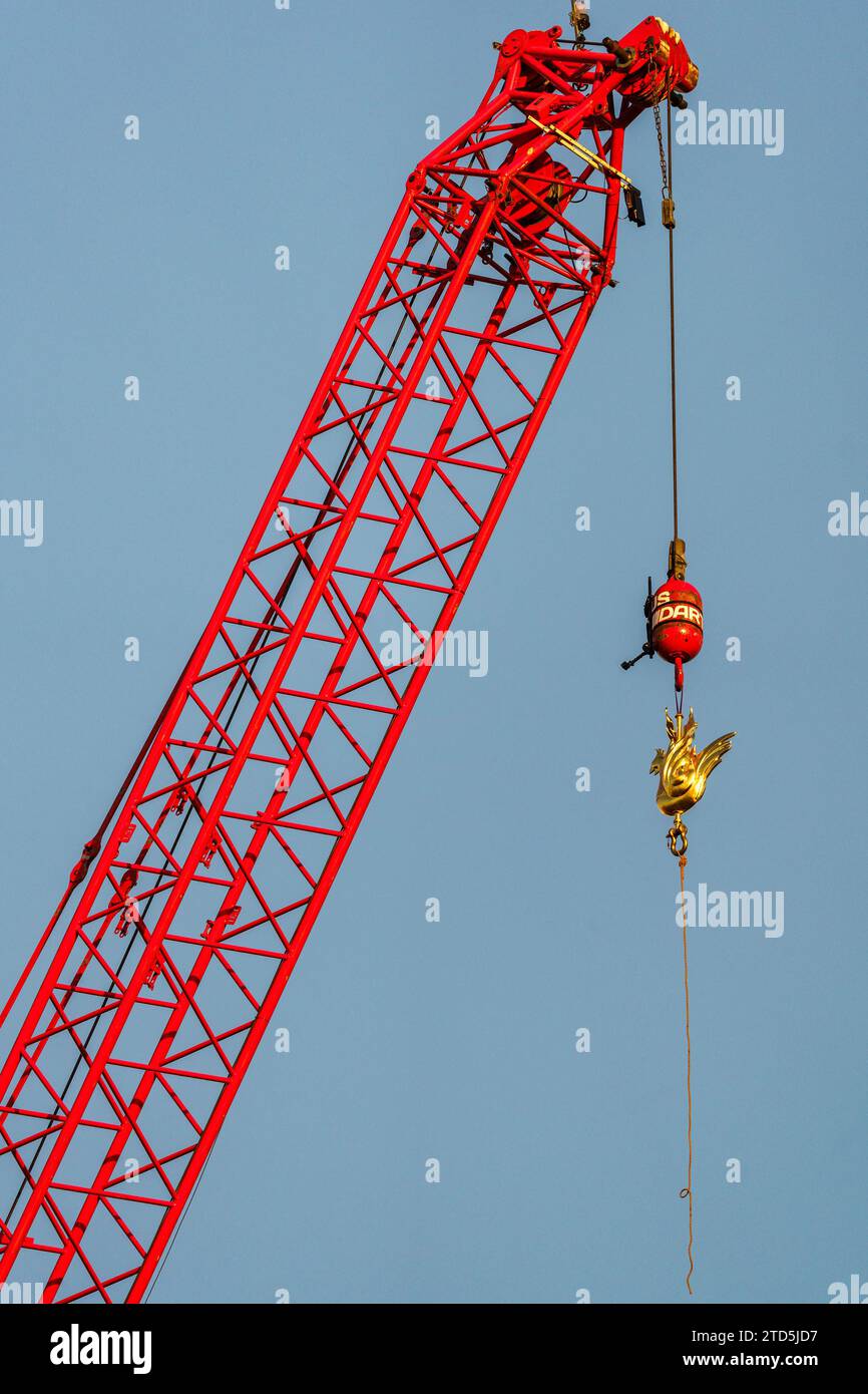 The new golden rooster containing relics is lifted by crane to be ...