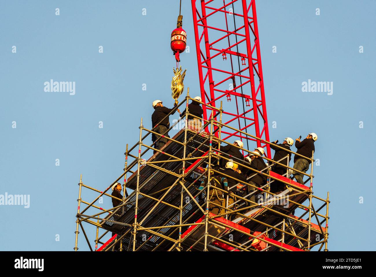 The new golden rooster containing relics is lifted by crane to be ...