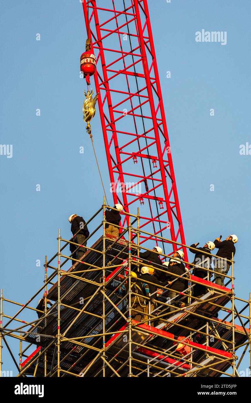 The new golden rooster containing relics is lifted by crane to be ...