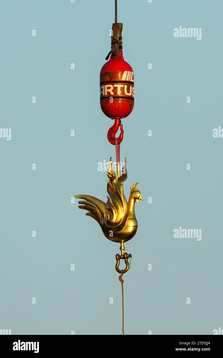 The new golden rooster containing relics is lifted by crane to be ...