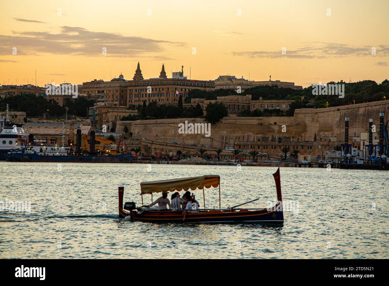 A Maltese gondola (or dghajsa) sails in front of the capital City ...