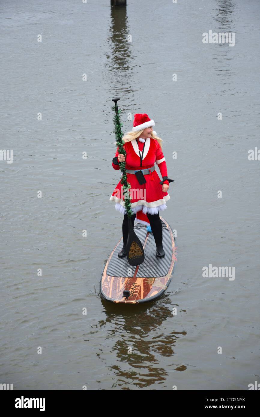 Lady paddle boarder on the water dressed as Santa. Christmas paddle ...