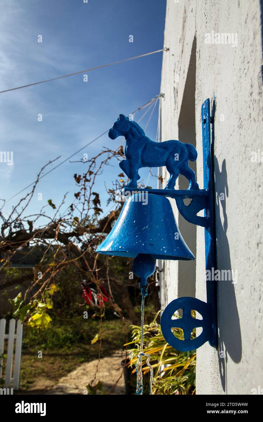 Blue painted iron bell with horse decorating the entrance of a ...