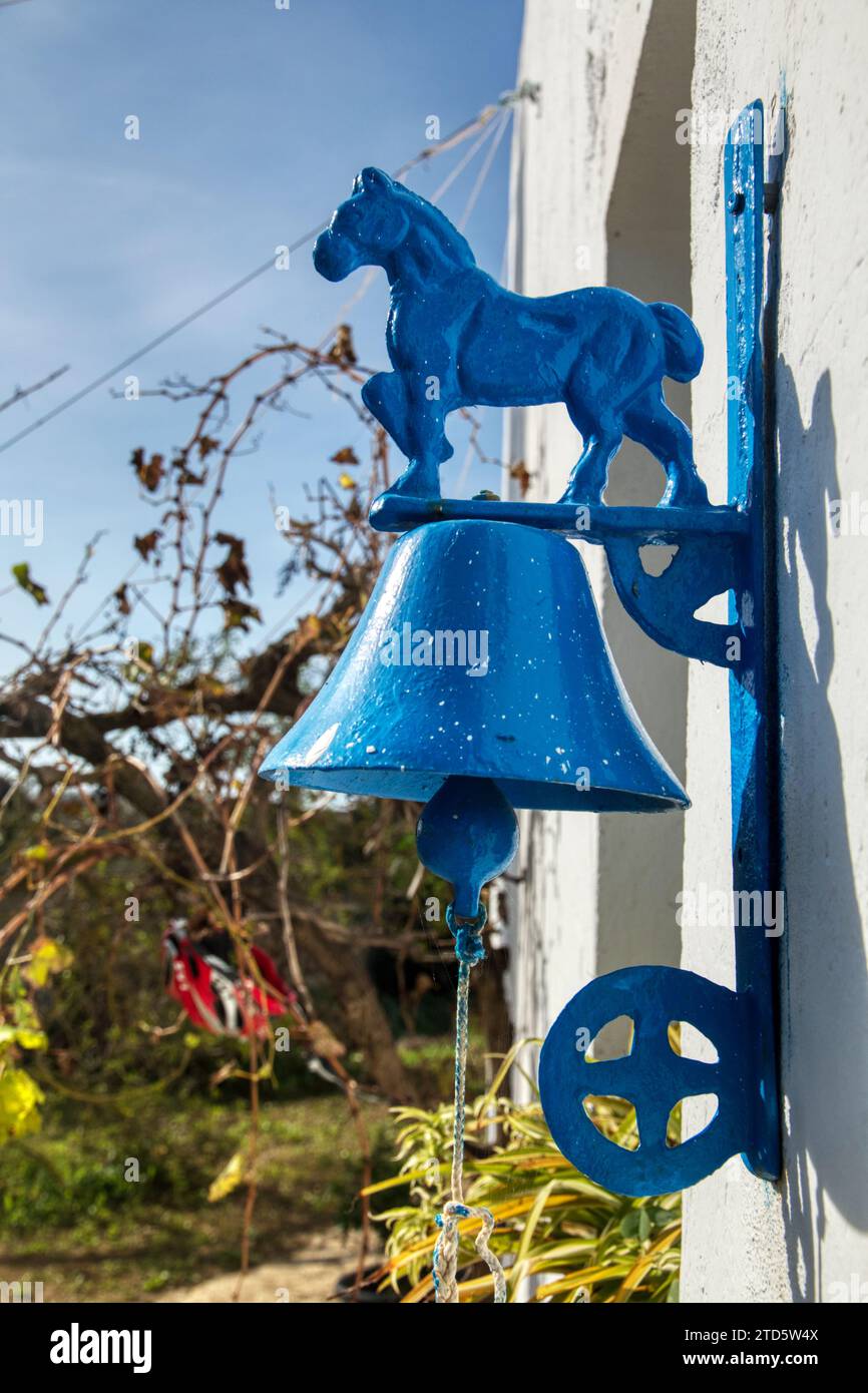 Blue painted iron bell with horse decorating the entrance of a ...