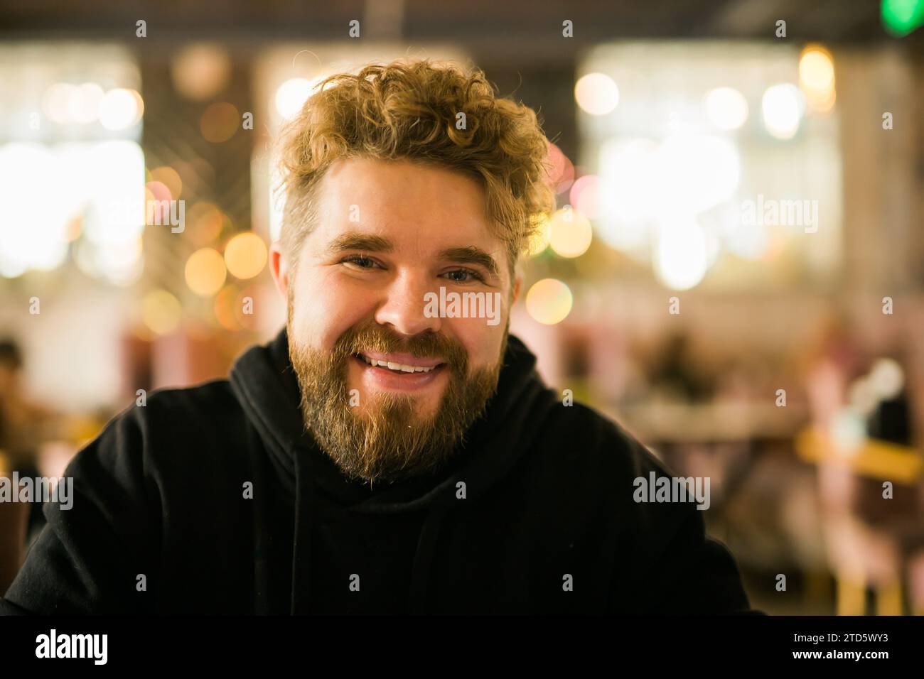 Bearded guy programmer or an entrepreneur in glasses in a stylish cafe ...