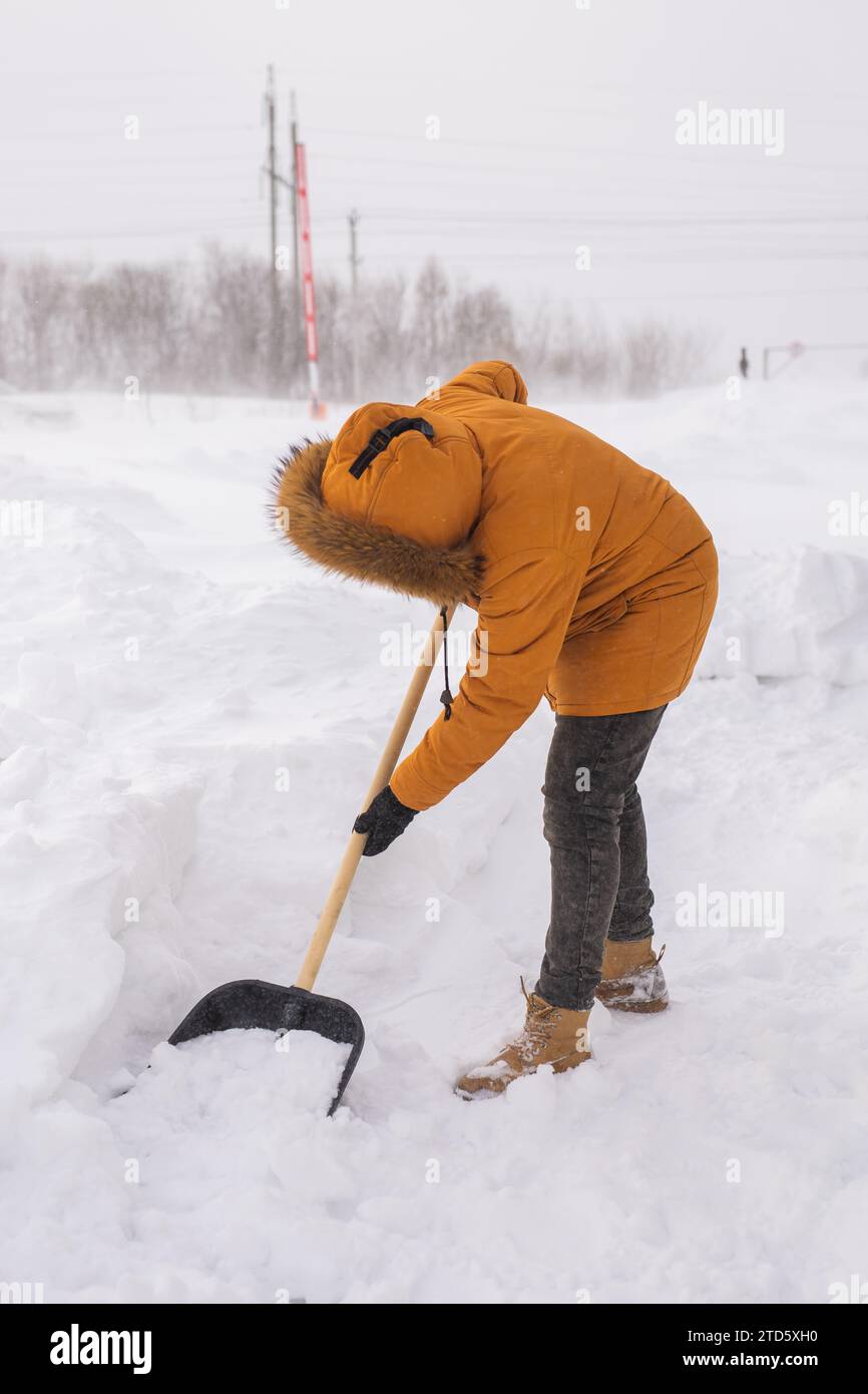 Young man clearing snow in his backyard village house with shovel ...