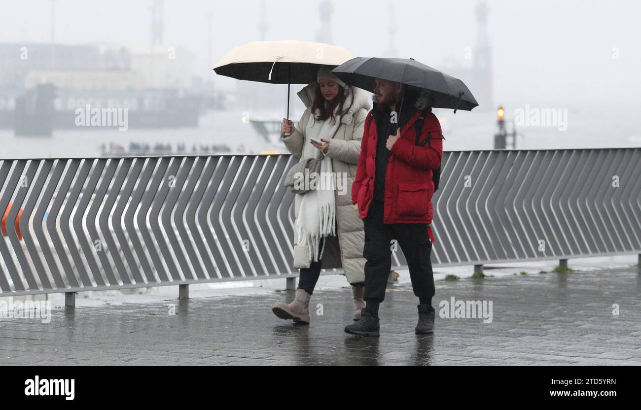 Passanten gehen bei Hamburger Schietwetter die Jan-Fedder-Promenade ...