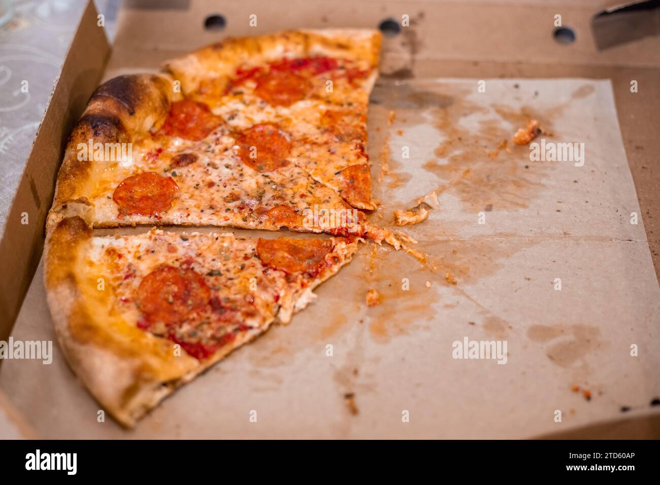 Half-eaten pizza in a cardboard box on the table. Fast food delivery ...