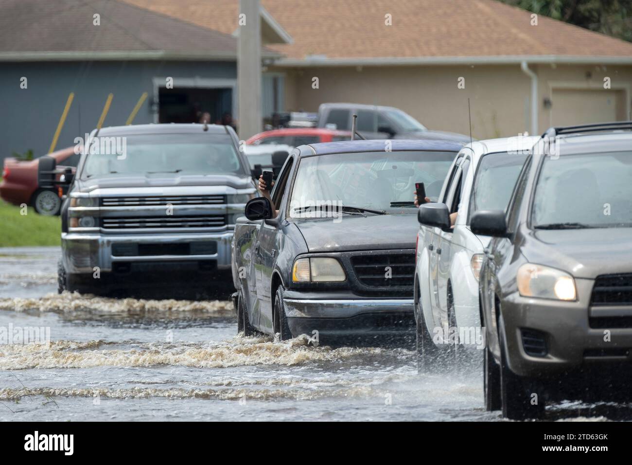 Hurricane flooded street with moving cars and surrounded with water ...
