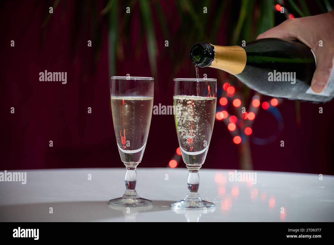 Pouring of brut champagne, cava or prosecco dry wine in glasses with ...