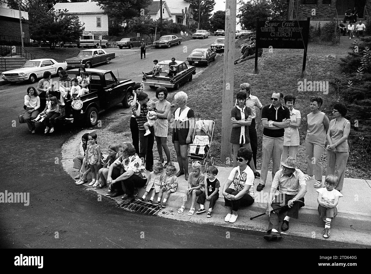 Independence, Missouri residents gather at a street corner to watch a ...