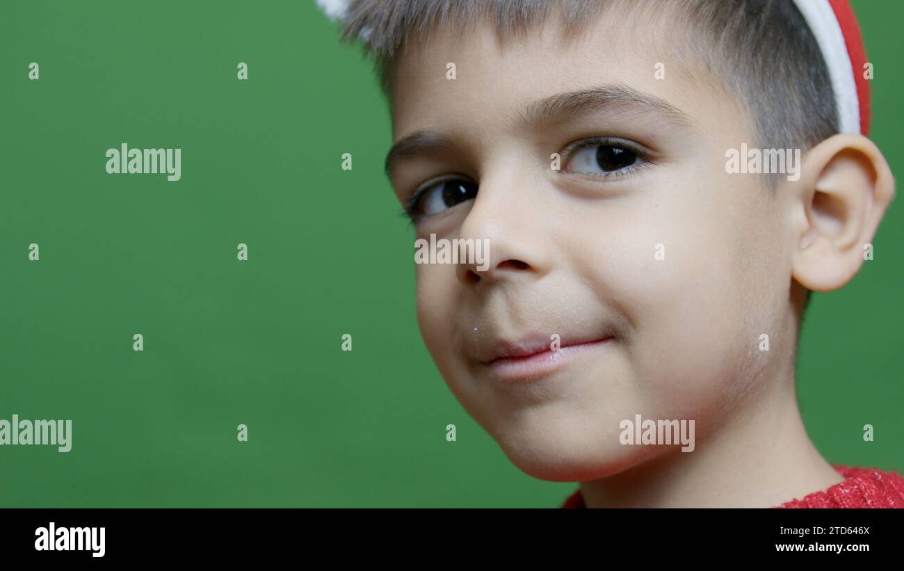 Side view of a cute cheeky child boy face. Isolate don green background ...