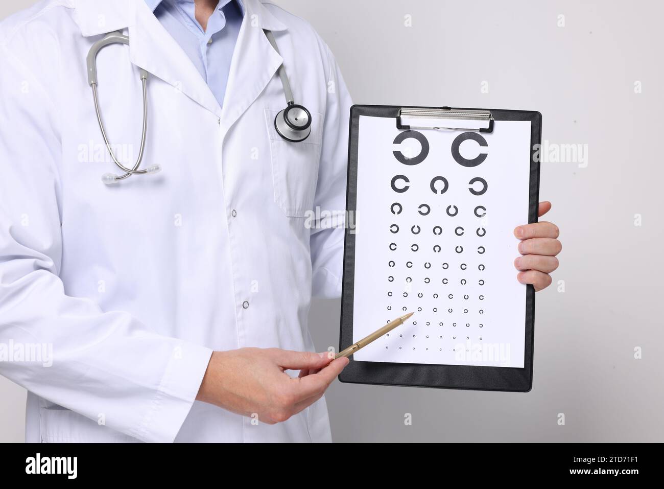 Ophthalmologist pointing at vision test chart on light background ...