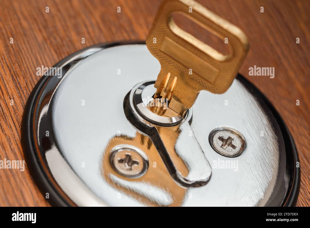 A yellow brass key is inserted into a cylinder lock. Macro photography ...