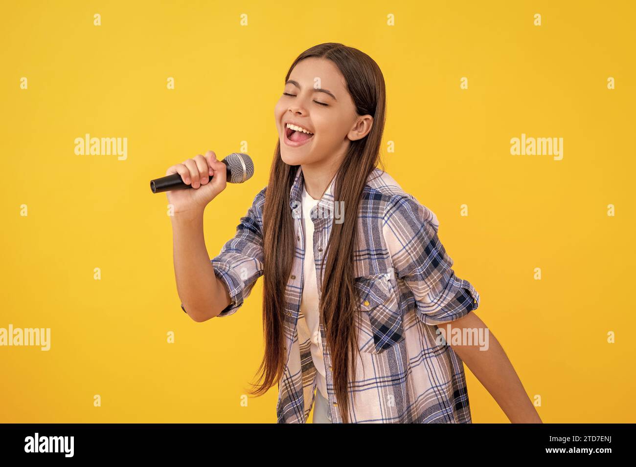 happy young girl singer perform karaoke isolated on yellow background ...