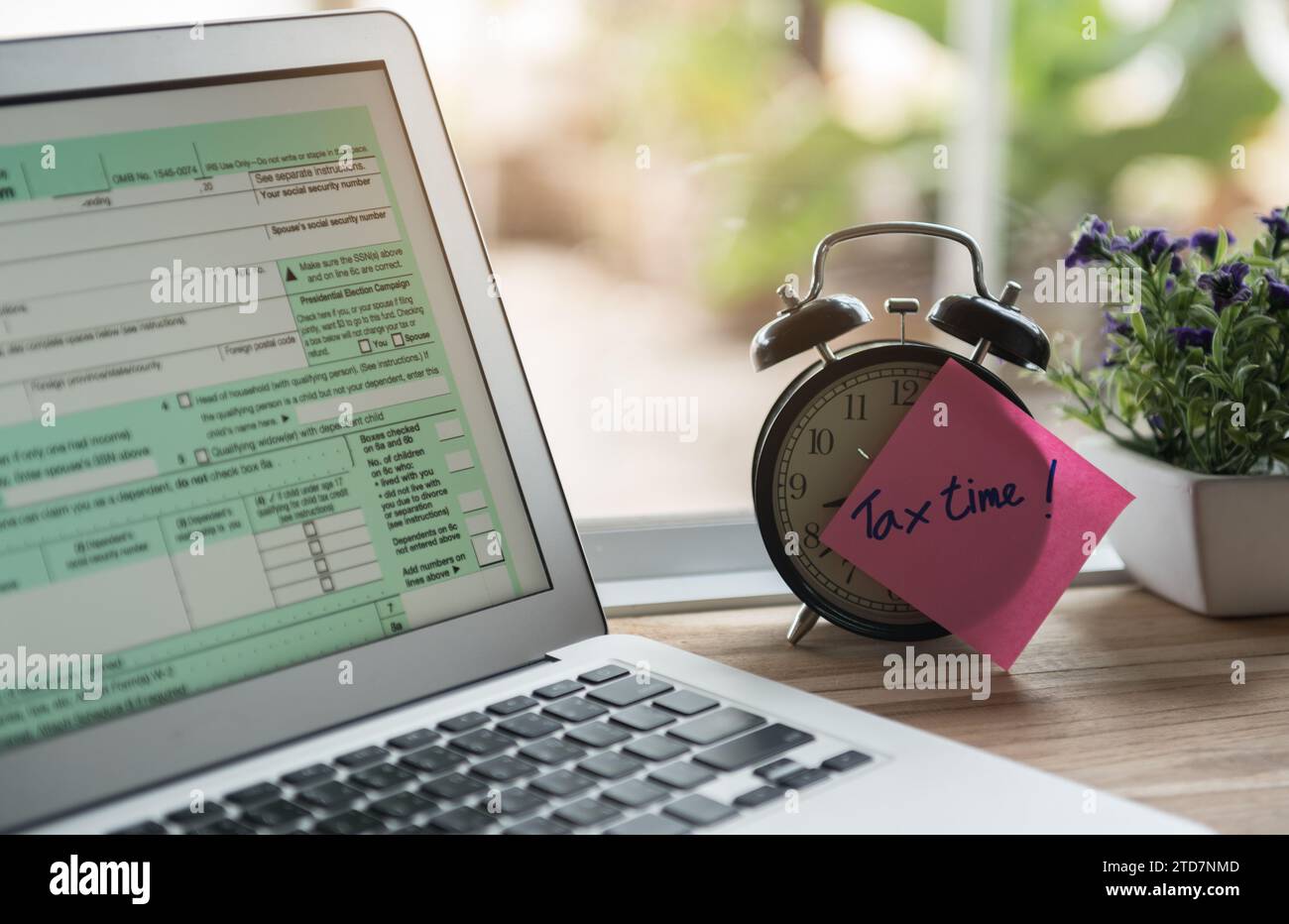 tax time post-it on alarm clock and Individual income tax return form ...