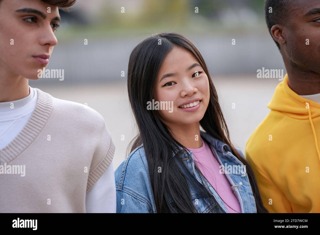 A young Asian woman smiles at the camera, flanked by her friends in a ...
