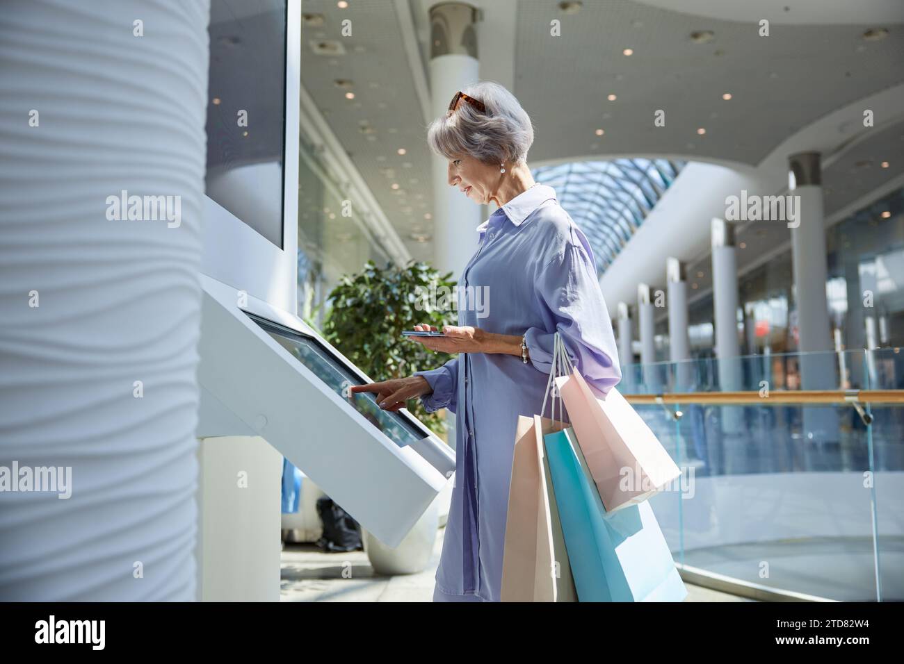 Senior old woman using atm machine for money withdrawing in shopping ...