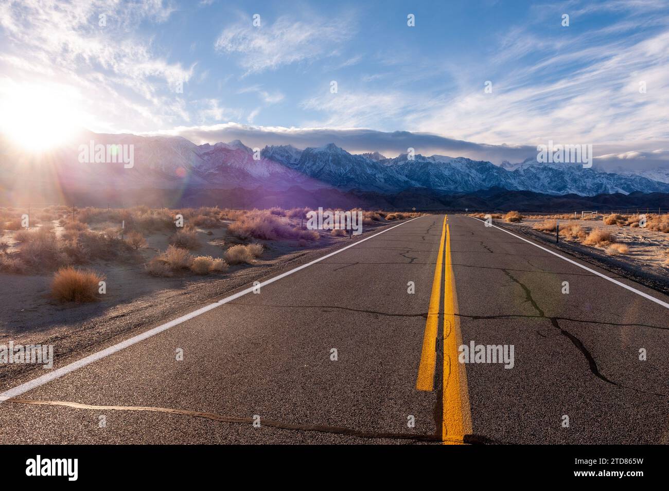 The towering mountains of the Sierra Nevada form a backdrop of the road ...