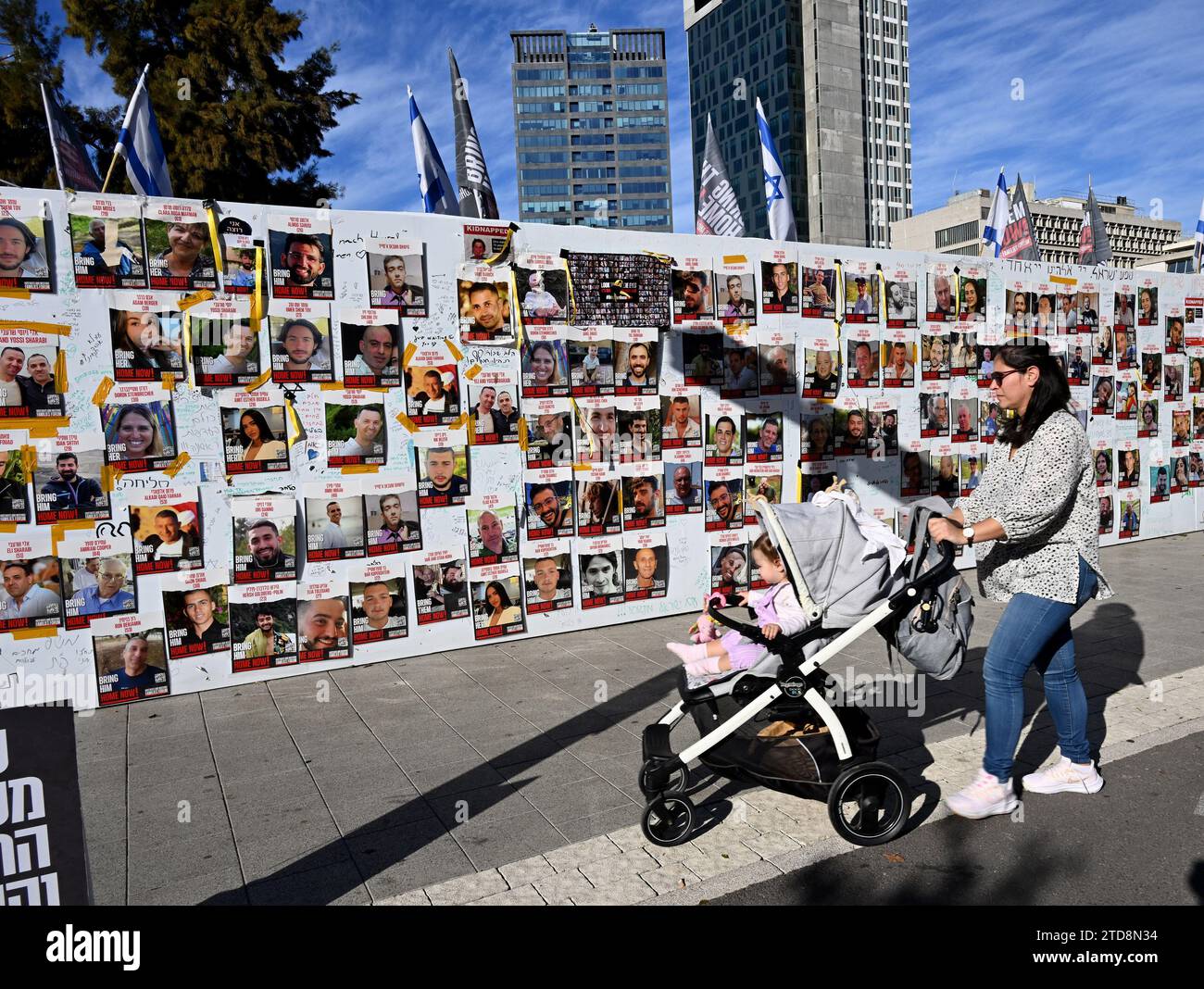 Tel Aviv, Israel. 16th Dec, 2023. People walk past a wall of photos of ...