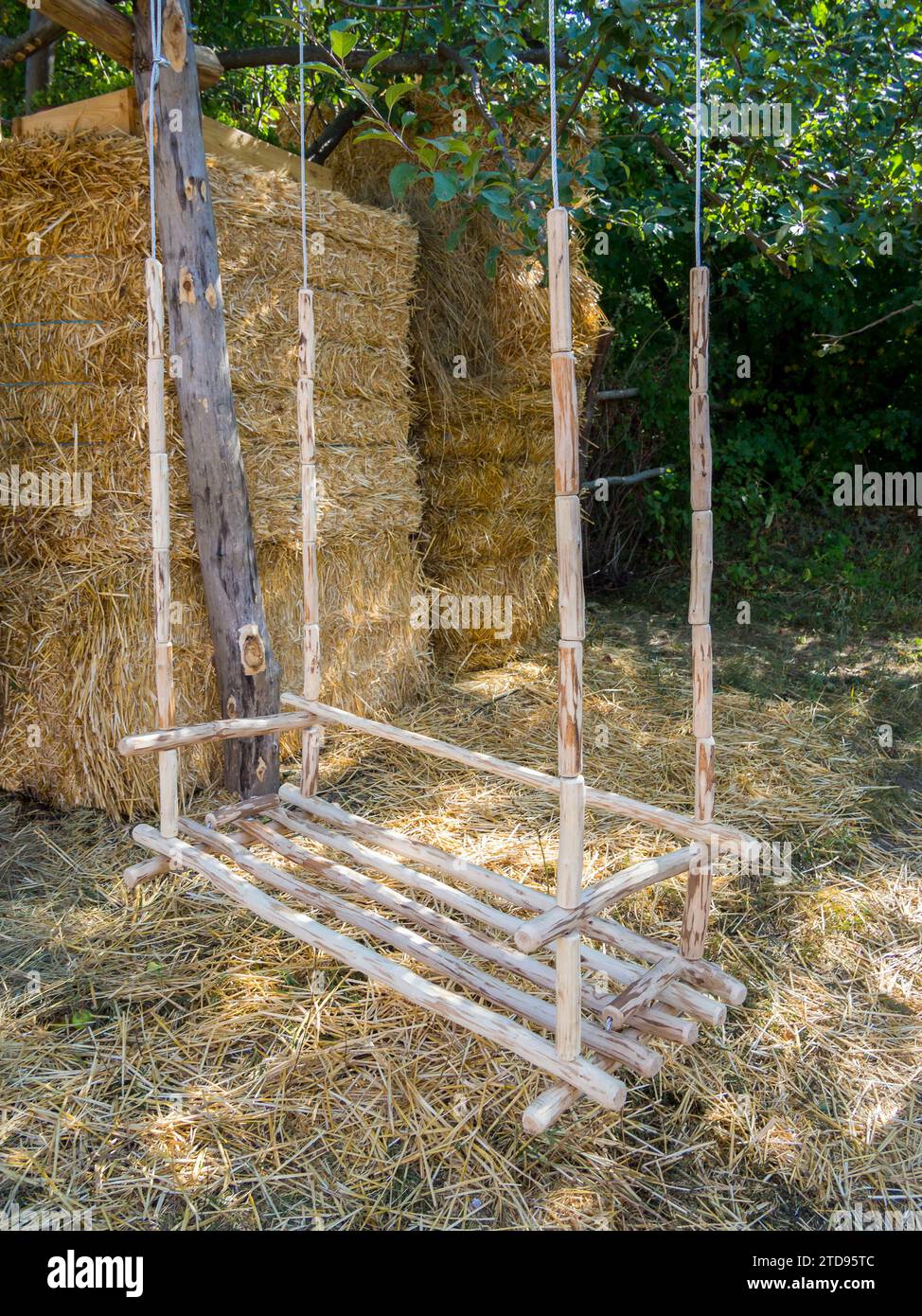 Hanging bench made from debarked wooden poles Stock Photo - Alamy