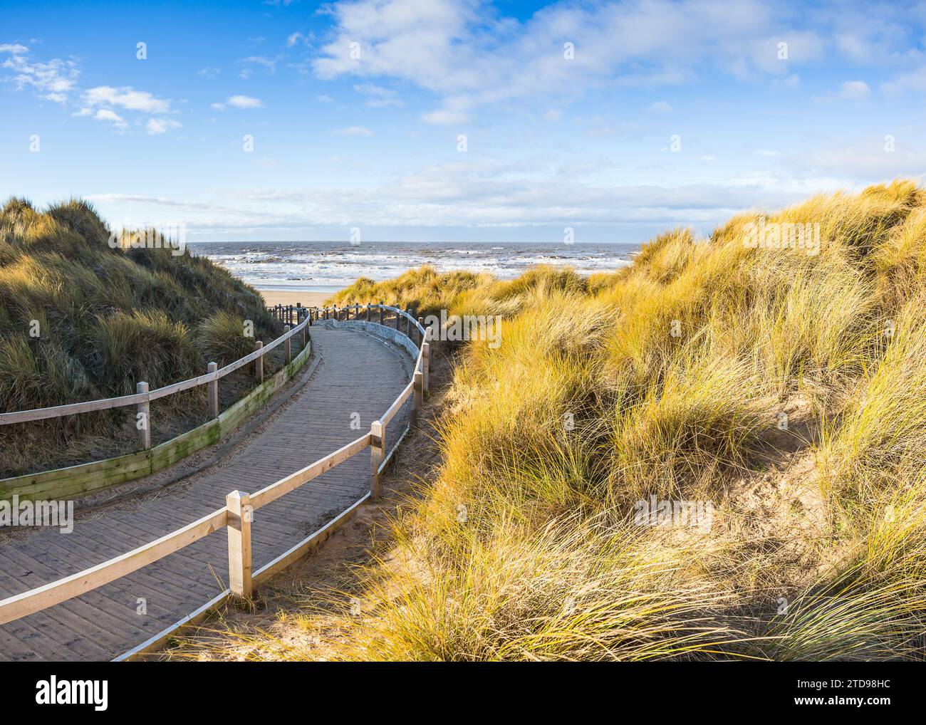 A multi image panorama of a curving board walk weaving through the sand ...