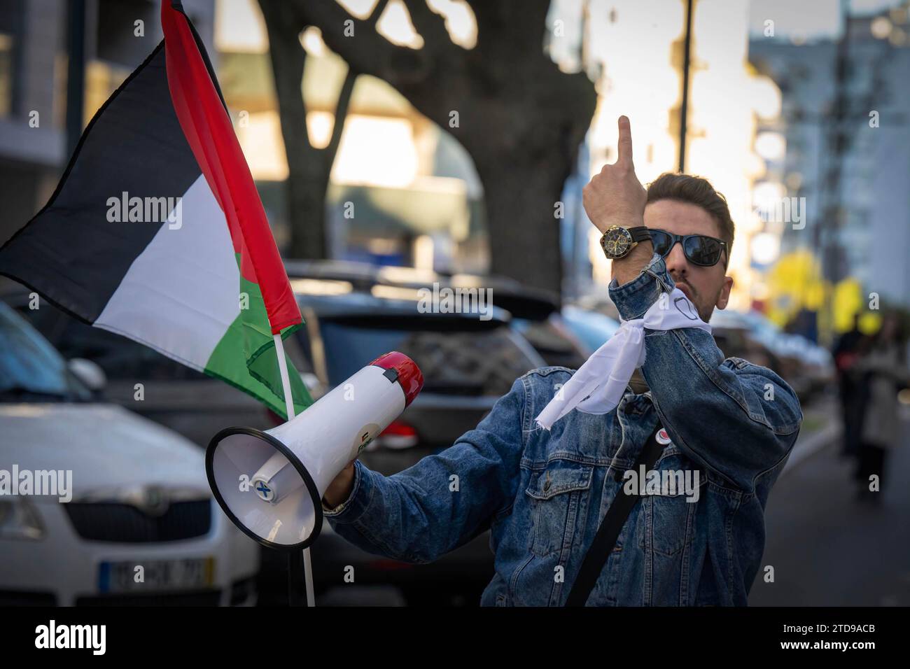 An activist with a Palestinian flag and a megaphone in his other hand ...