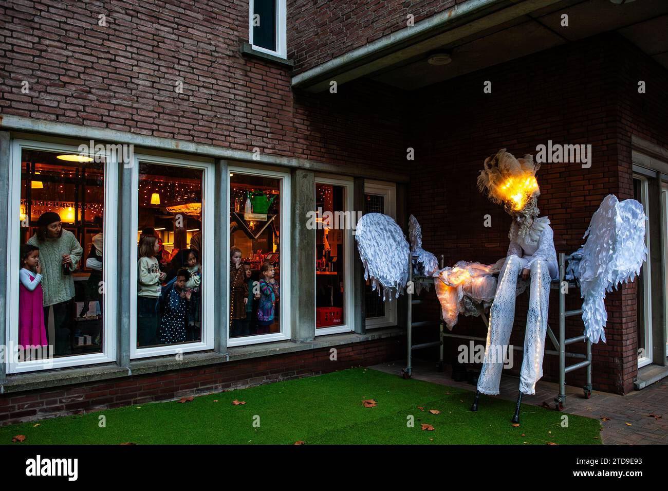 A woman prepares under the watchful eye of a group of children. The ...