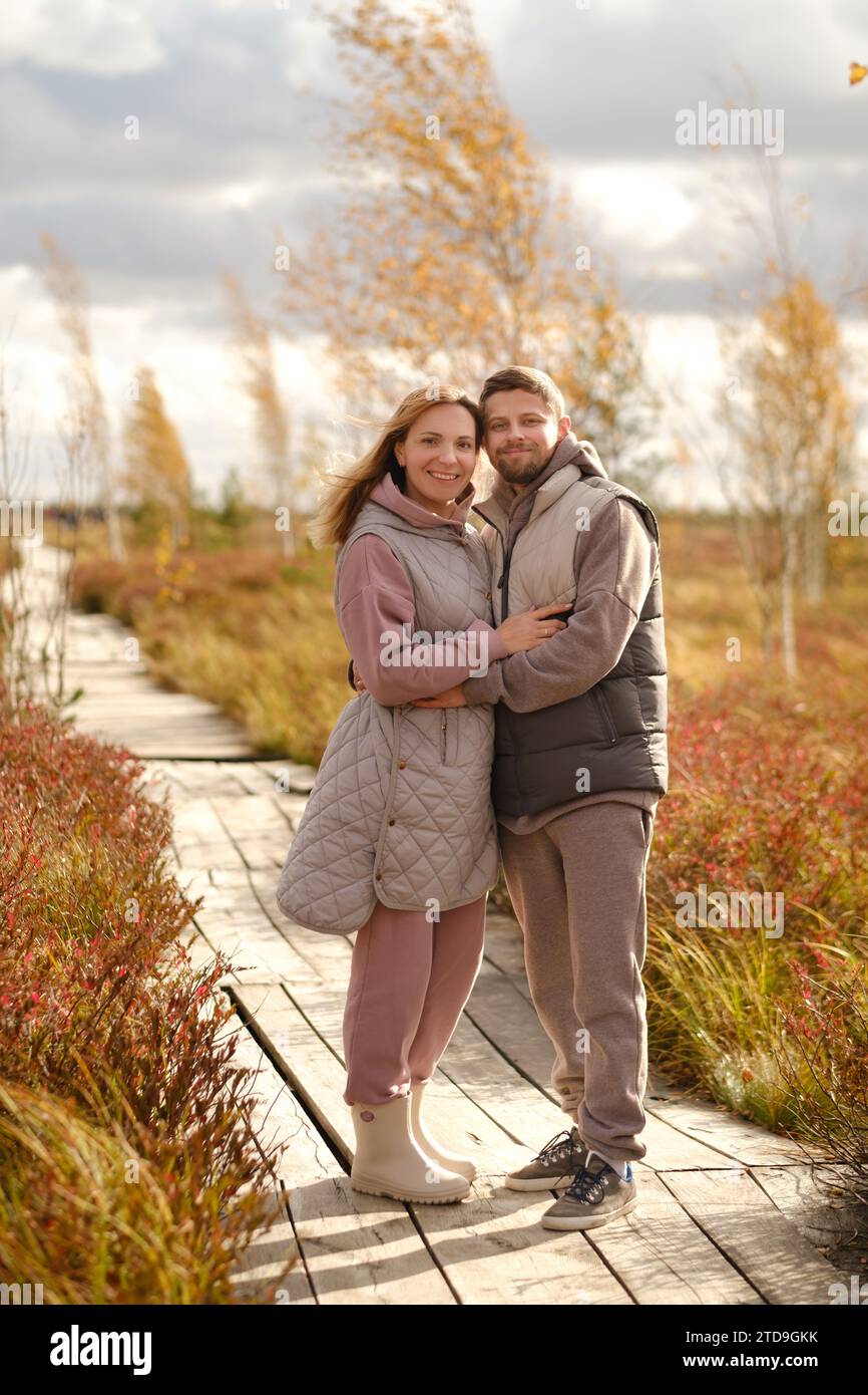 People in boots stand hugging on a wooden path in a swamp in Yelnya ...