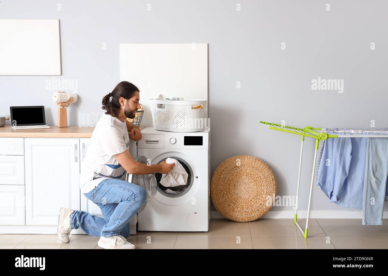 Young man putting laundry into washing machine at home Stock Photo - Alamy