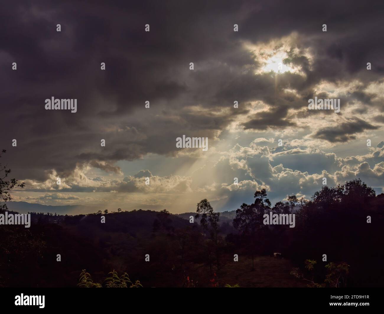 A beam of sun light emerges from dense clouds in the sky over the ...