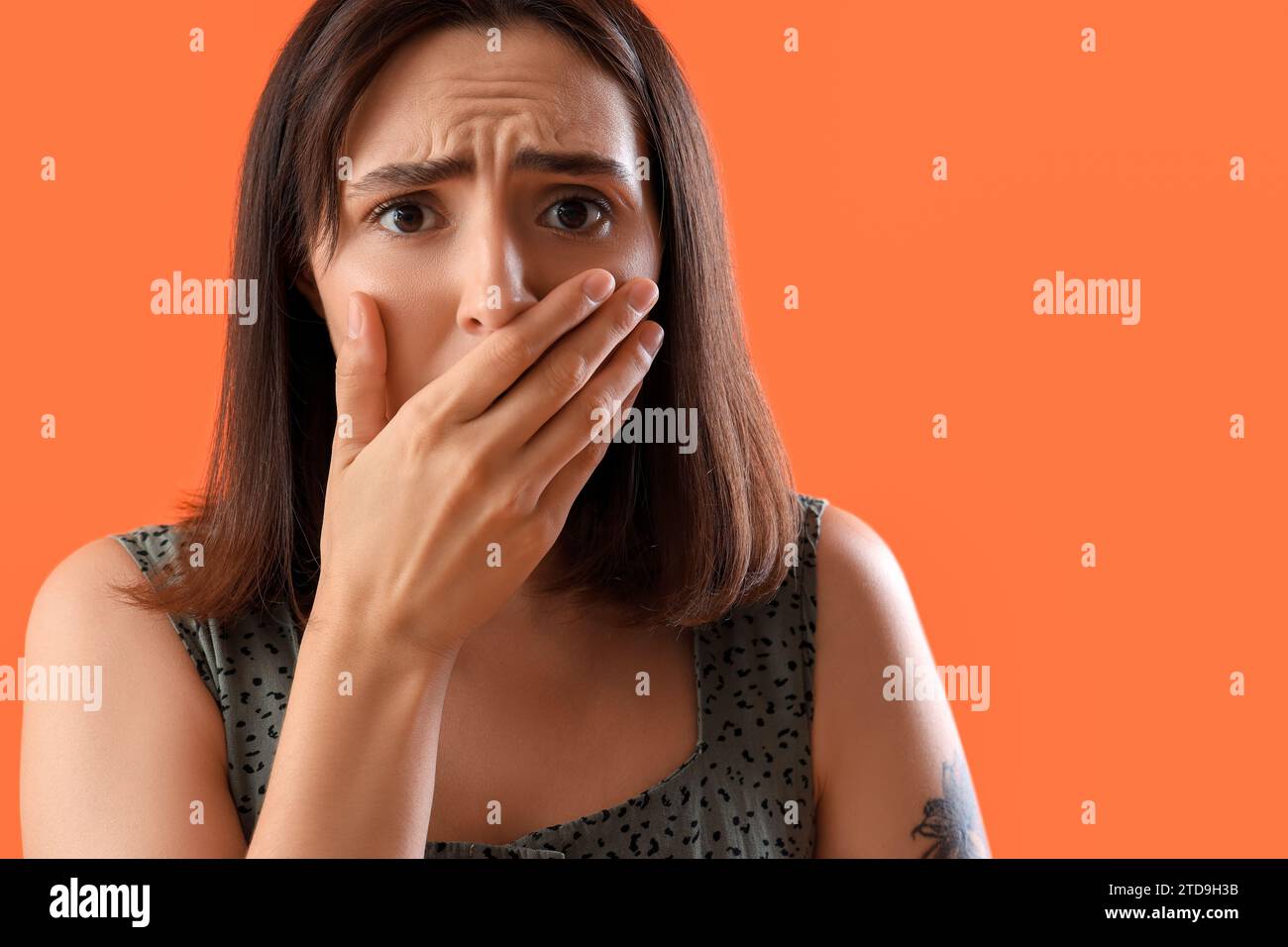 Beautiful young afraid woman on orange background Stock Photo - Alamy