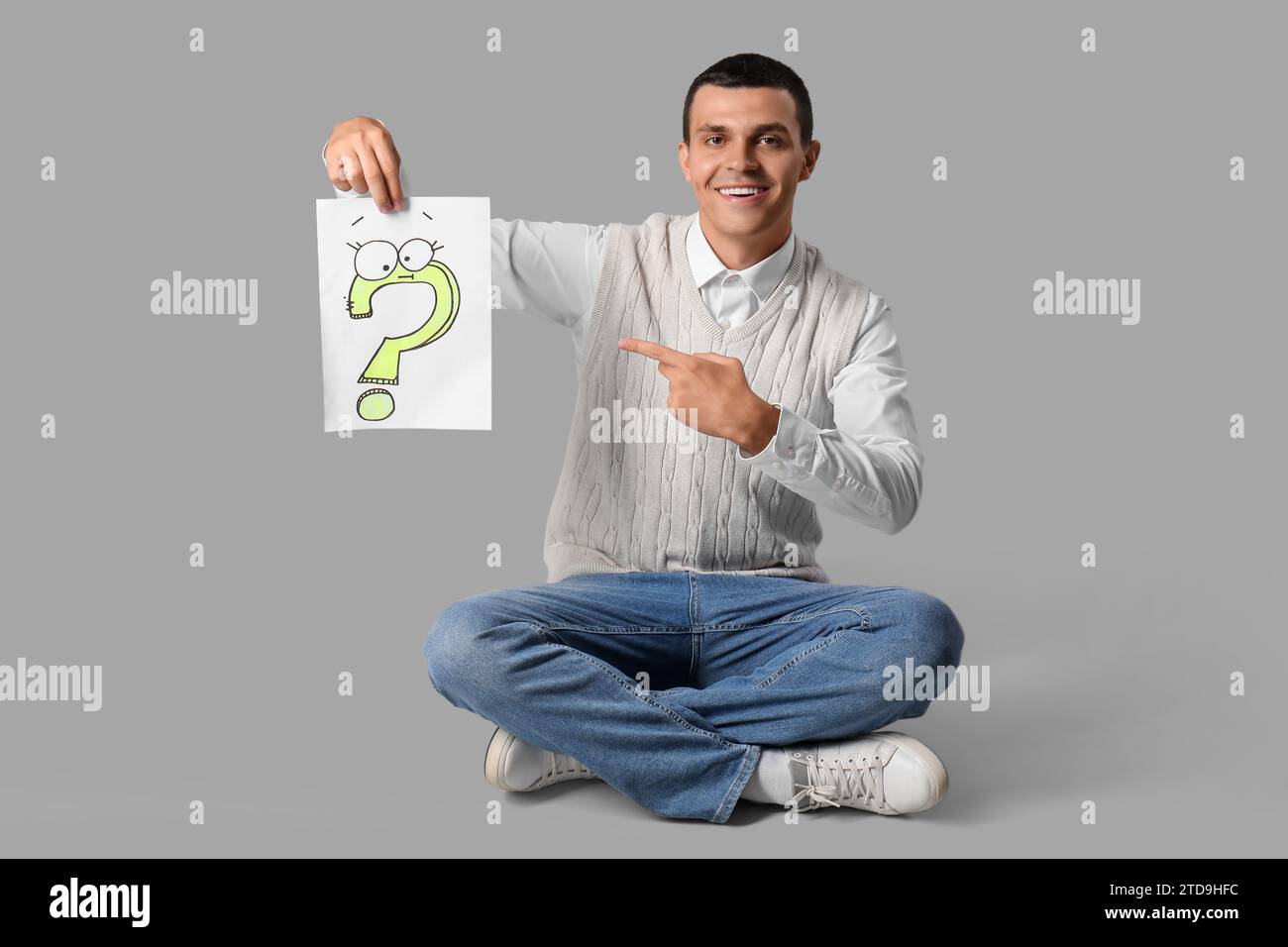 Young man pointing at paper with question mark on grey background Stock ...