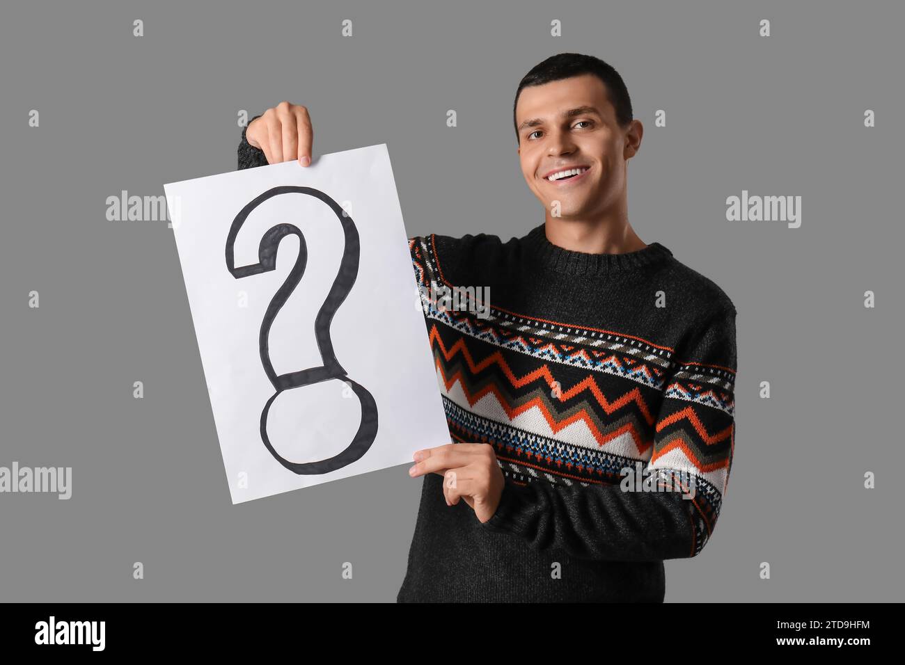 Young man holding paper with question mark on grey background Stock ...
