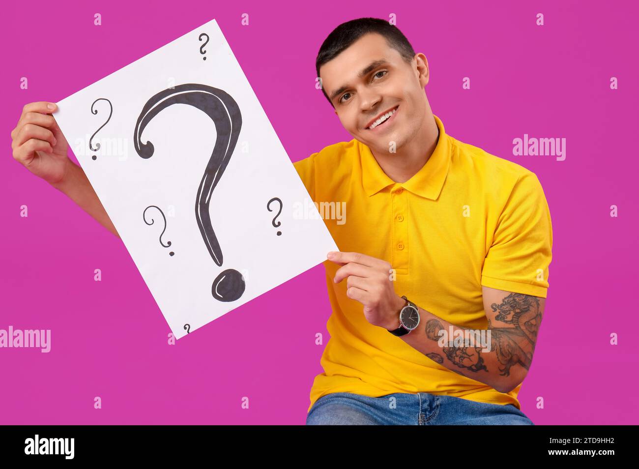 Young man holding paper with question marks on purple background Stock ...