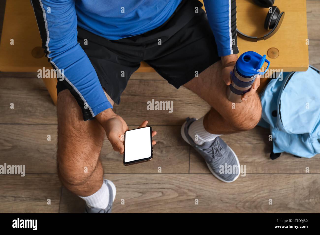 Sporty young man with mobile phone in locker room, top view Stock Photo ...