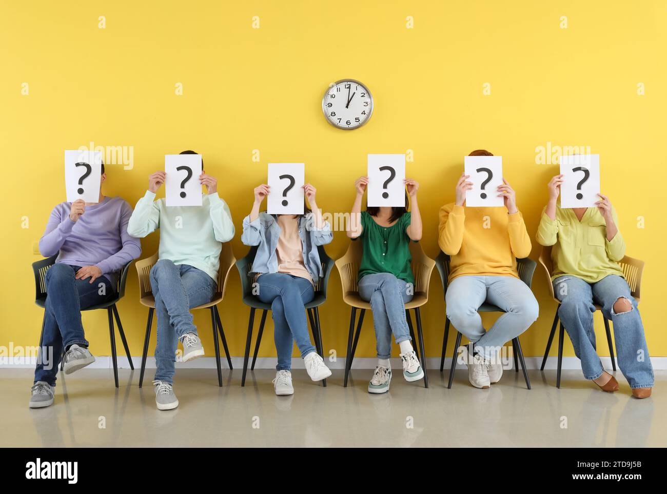 Applicants holding paper sheets with question marks in room Stock Photo ...