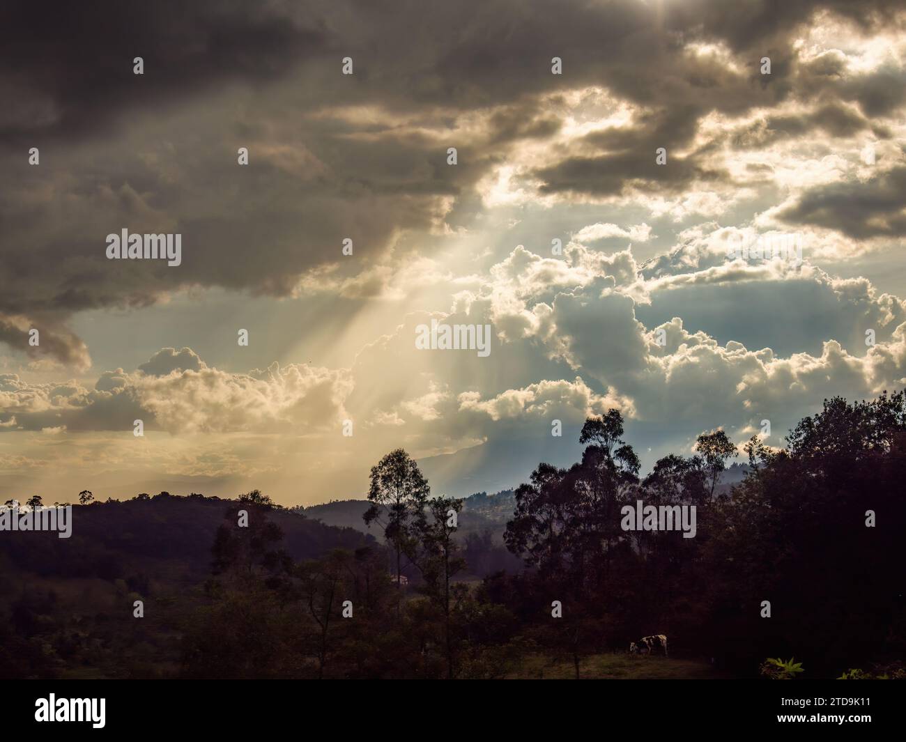 A beam of sun light emerges from dense clouds in the sky over the ...
