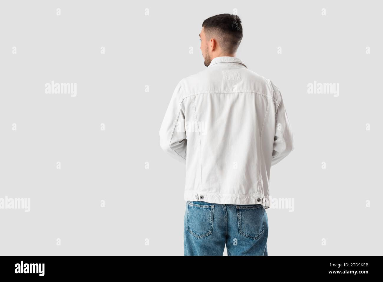 Stylish young man in denim jacket on white background, back view Stock ...