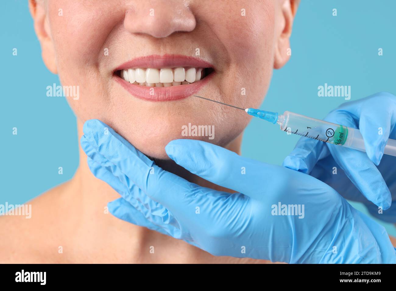 Beautiful mature woman receiving injection on blue background, closeup ...