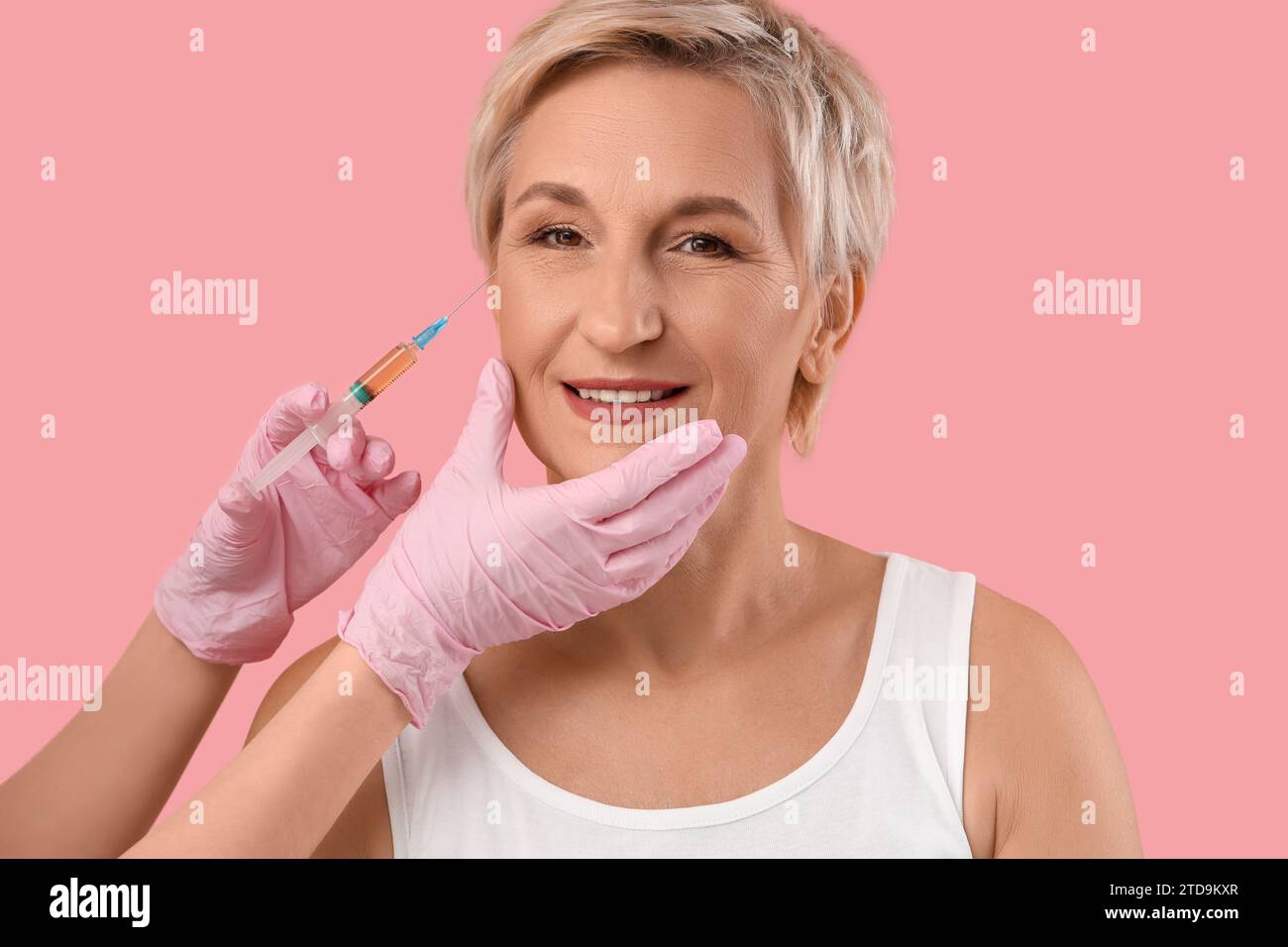 Beautiful mature woman receiving injection on pink background, closeup ...