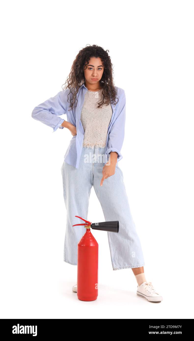 Upset young African-American woman with fire extinguisher on white ...