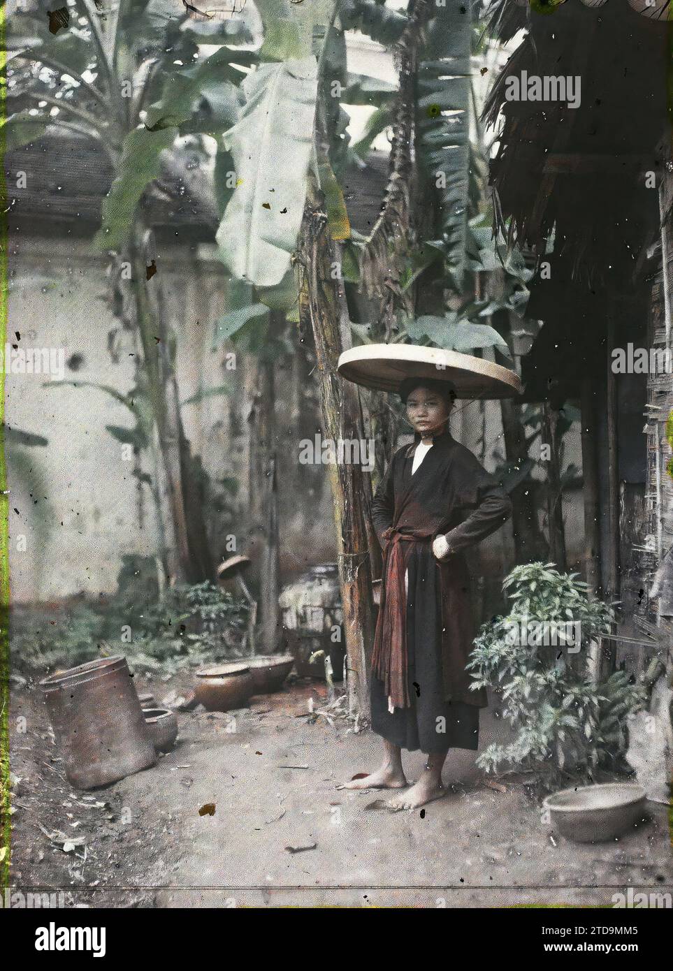 Tonkin, Indochina A young girl in a corner of a courtyard planted with ...