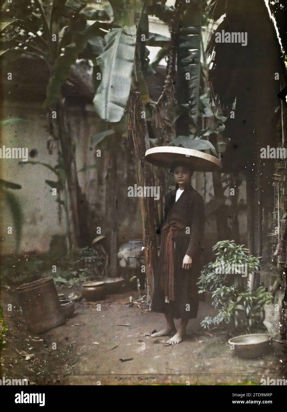 Tonkin, Indochina A young girl in a corner of a courtyard planted with ...