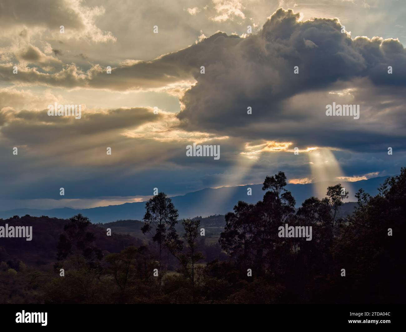 Some sun beams come trough dense clouds, in an overcast sunset over the ...