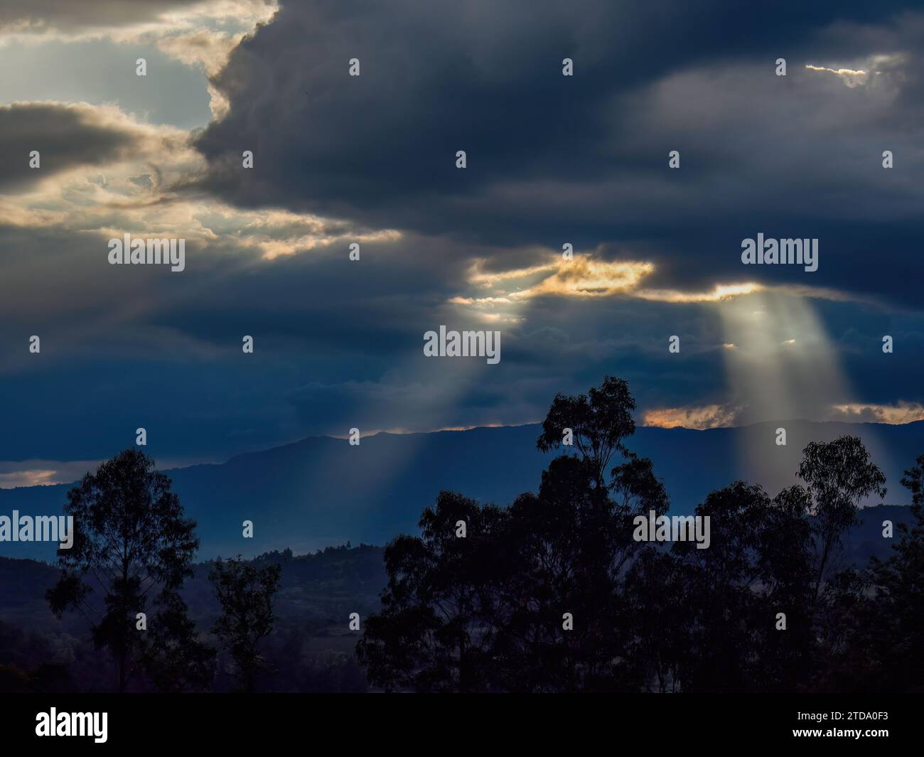 Some sun beams come trough dense clouds, in an overcast sunset over the ...