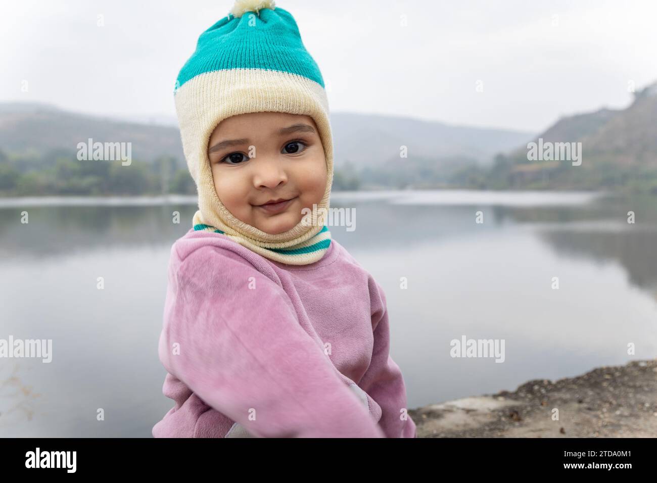 cute infant in winter dress and monkey cap innocent facial expression ...