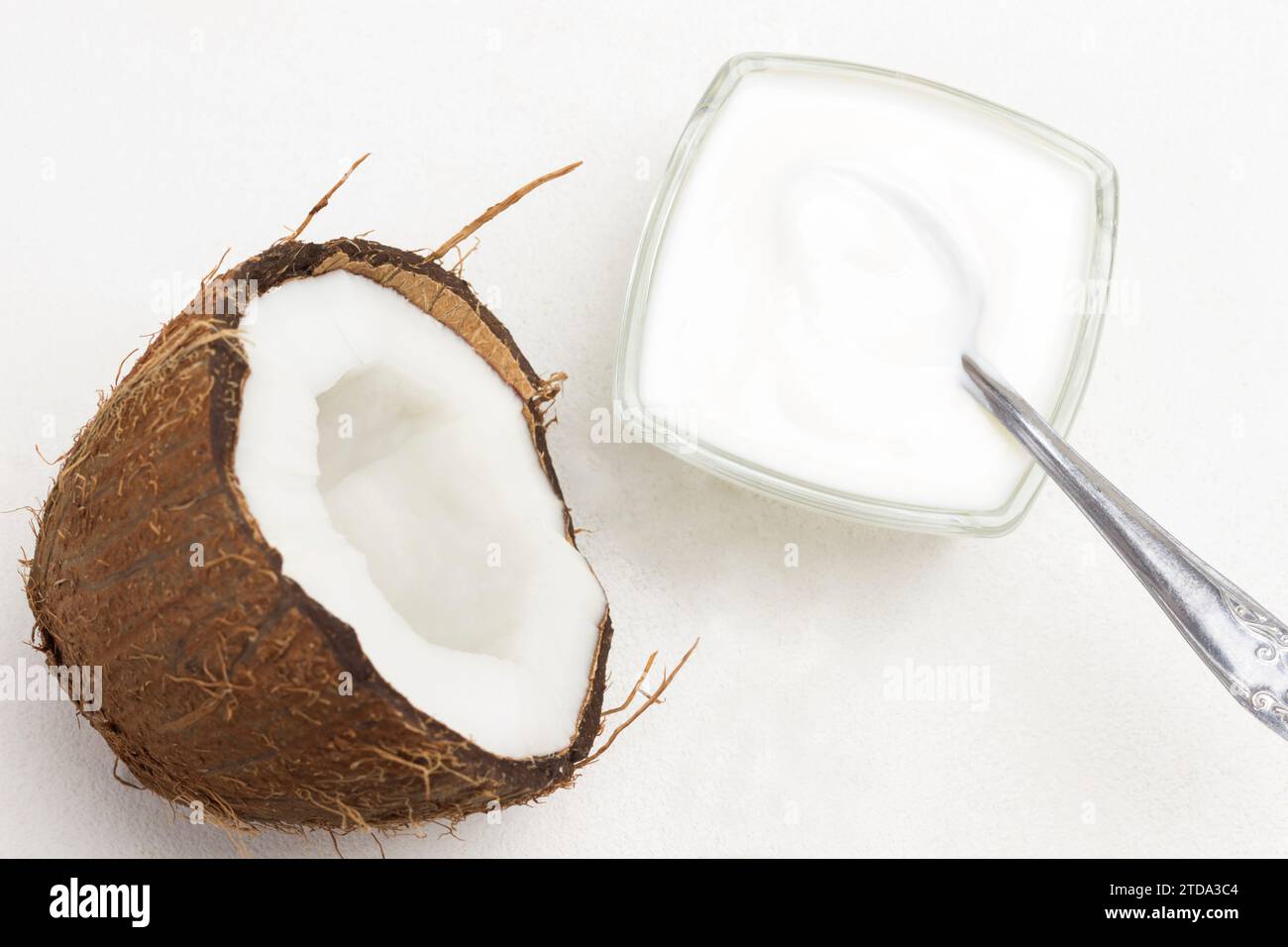 Half fresh coconut. Bowl of yogurt and spoon. White background. Flat ...