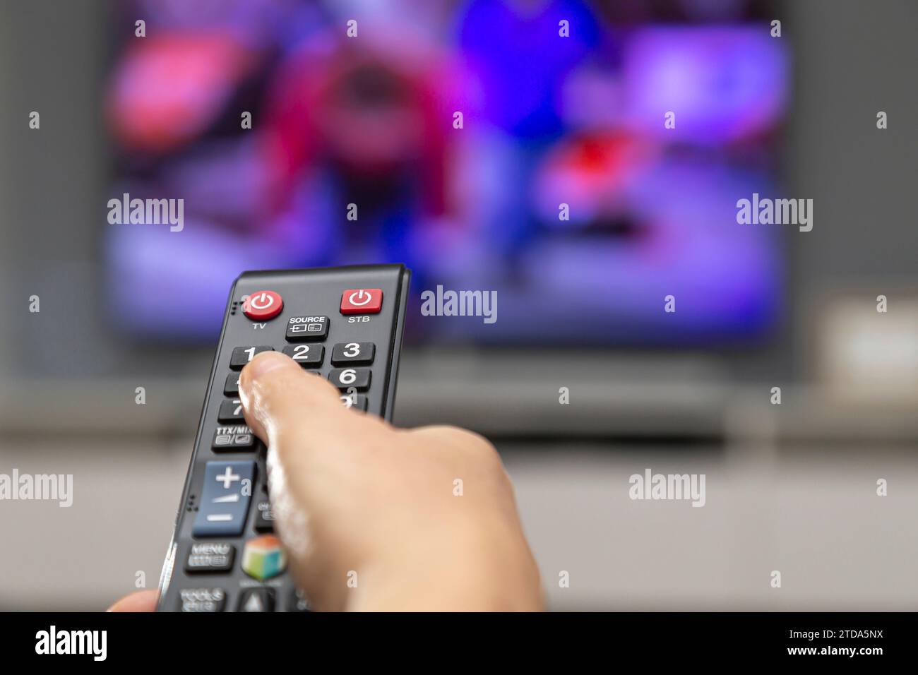A woman's hand with a remote control switches channels on the TV Stock ...