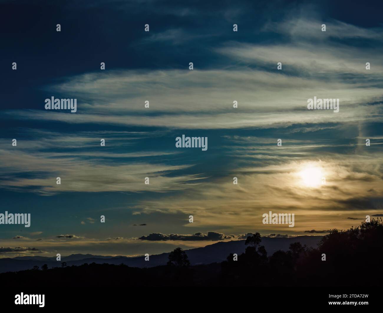 The sun barely hidden behind a translucent cloud in the sunset over the ...